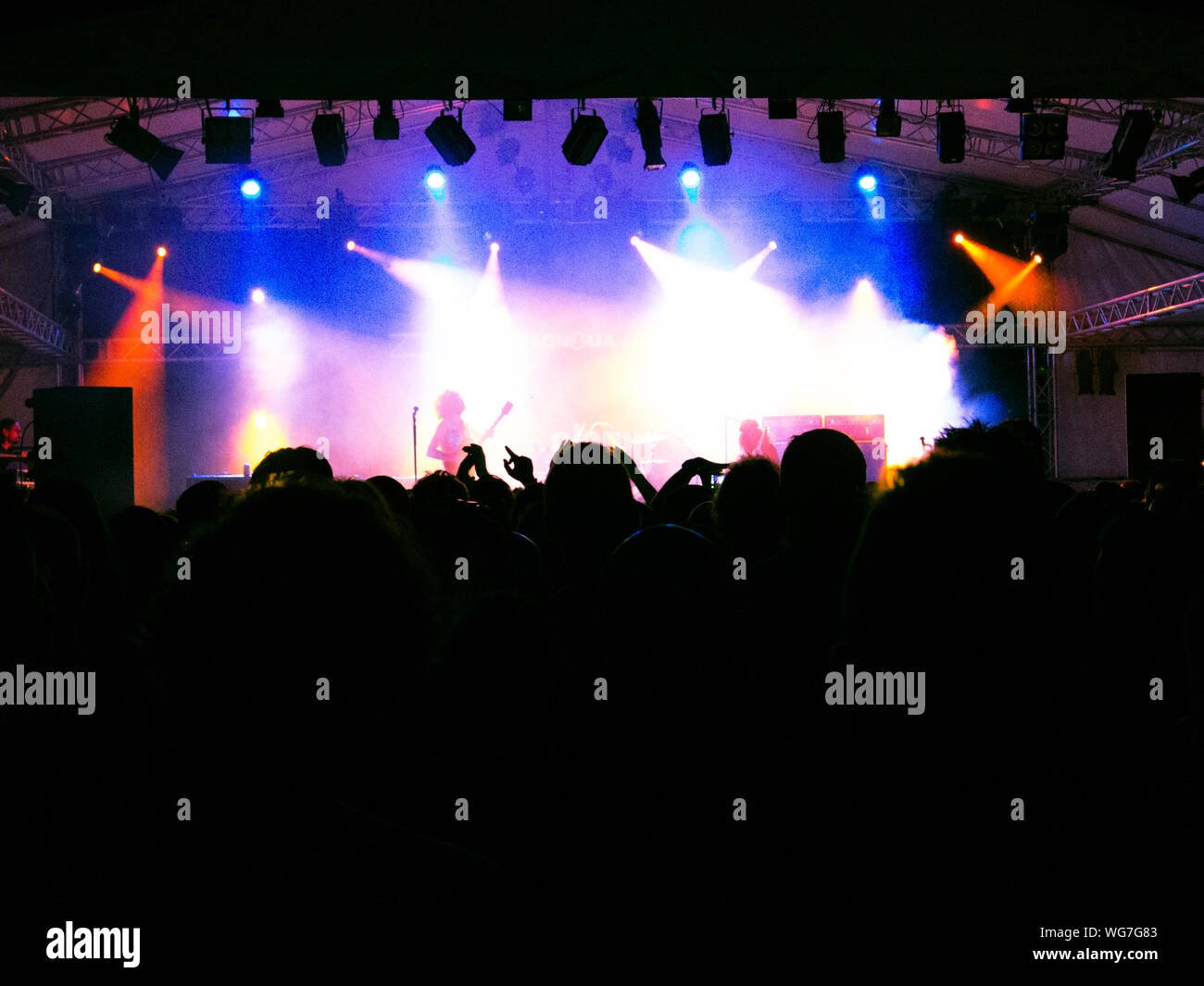 Concert crowd clapping in front of a bright stage Stock Photo - Alamy