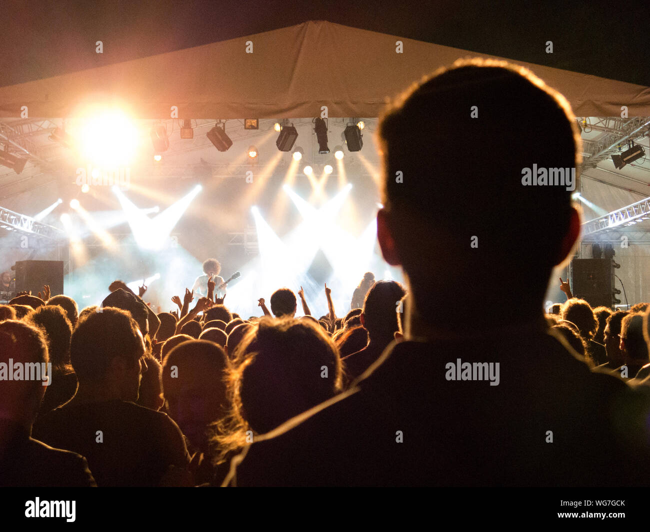Concert crowd clapping in front of a bright stage Stock Photo - Alamy