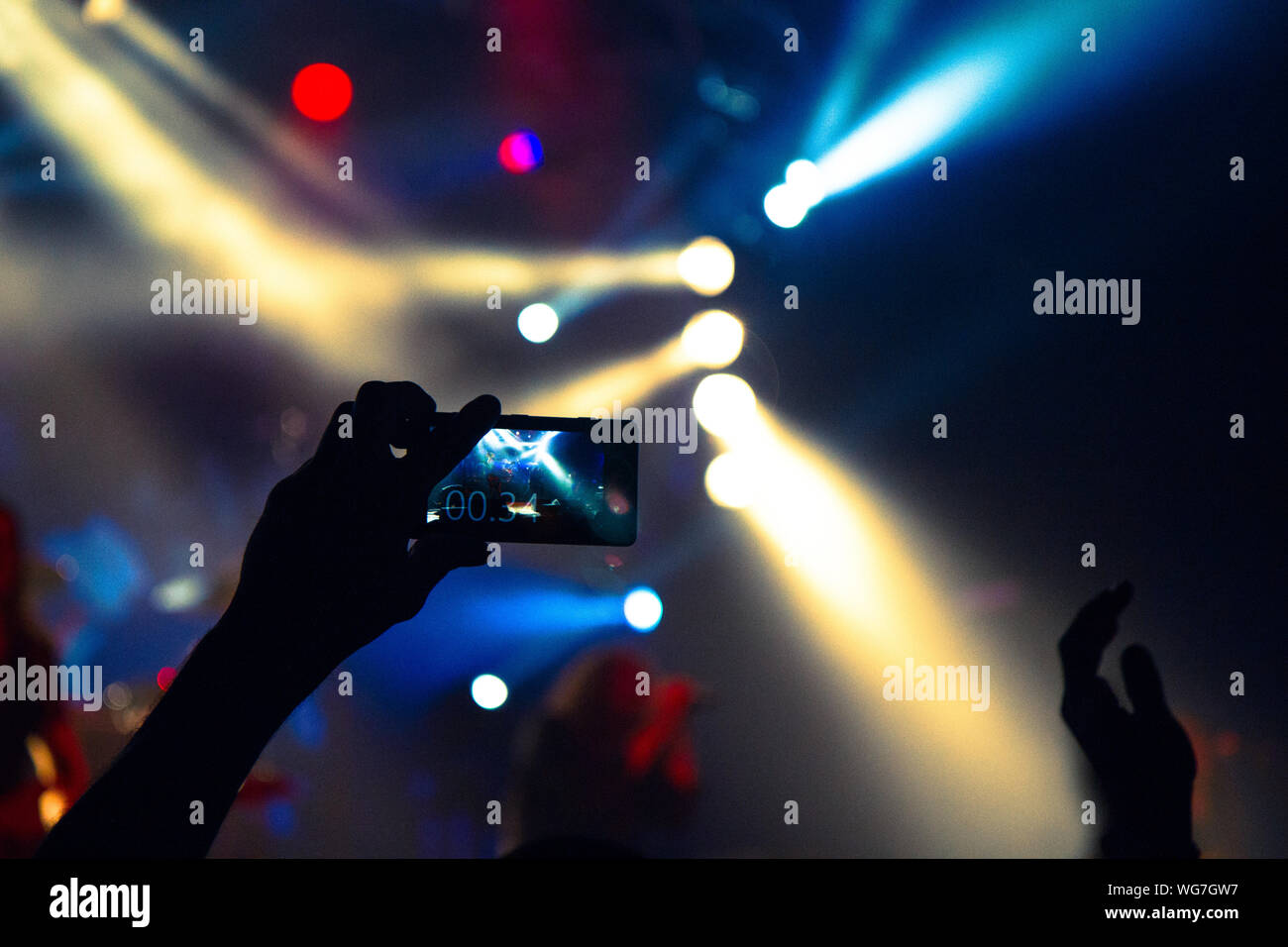 Concert crowd clapping in front of a bright stage Stock Photo - Alamy