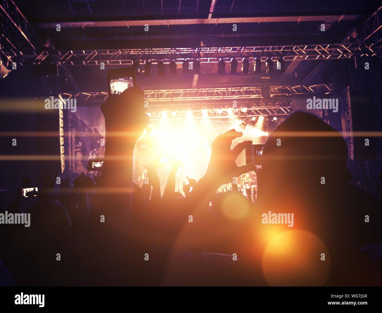 Concert crowd clapping in front of a bright stage Stock Photo - Alamy