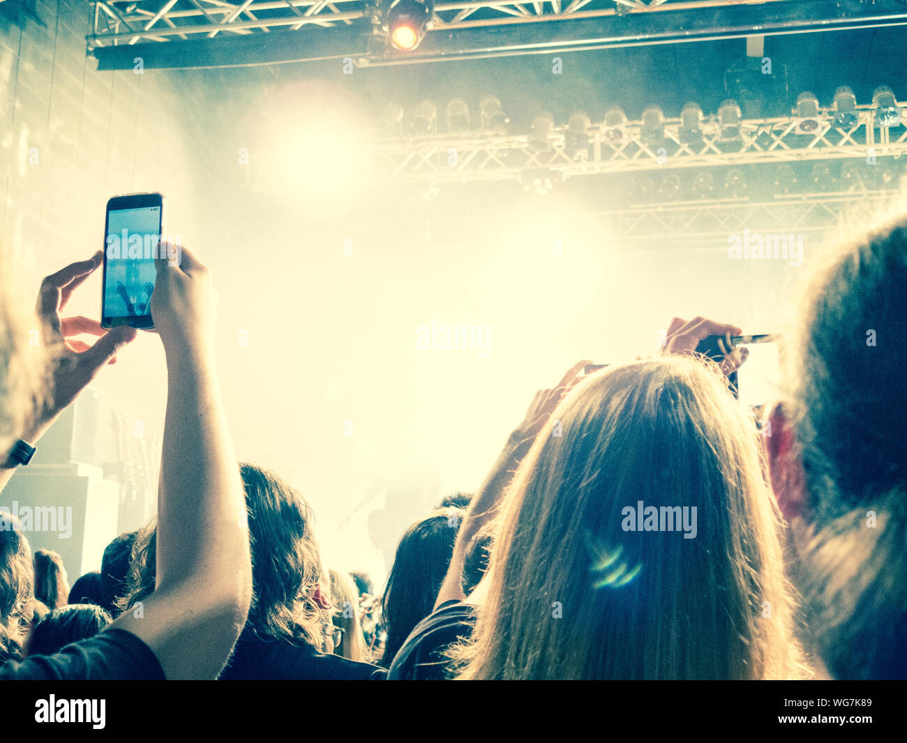 Concert crowd clapping in front of a bright stage Stock Photo - Alamy