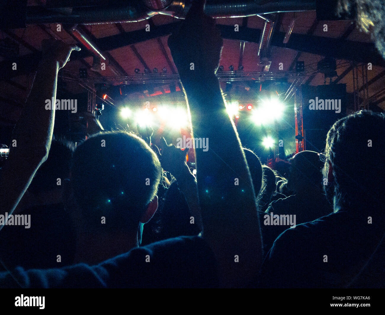 Concert crowd clapping in front of a bright stage Stock Photo - Alamy
