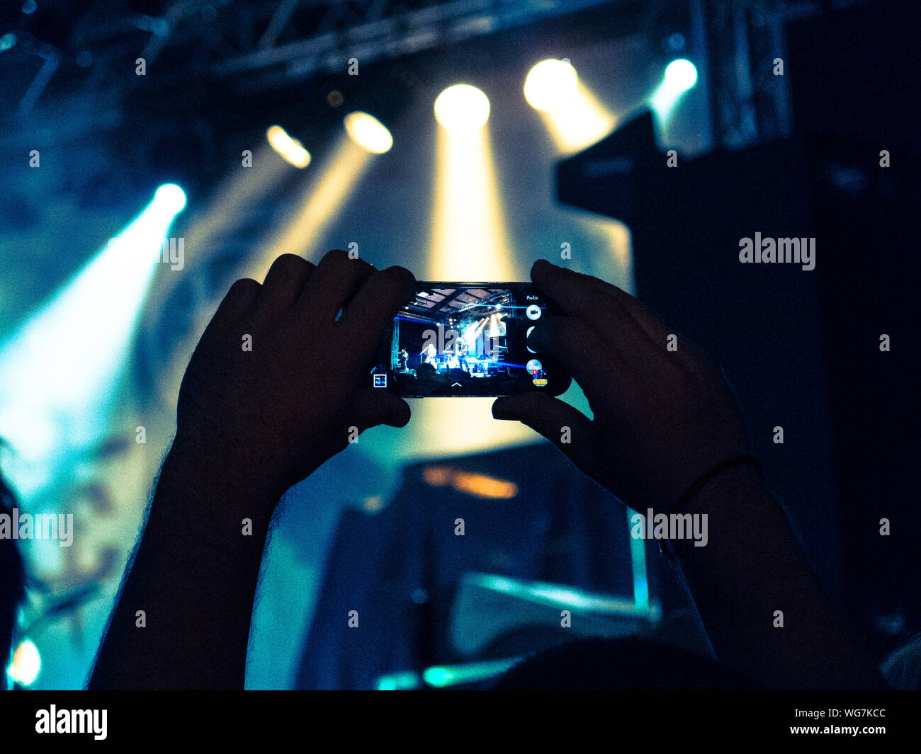 Concert crowd clapping in front of a bright stage Stock Photo - Alamy