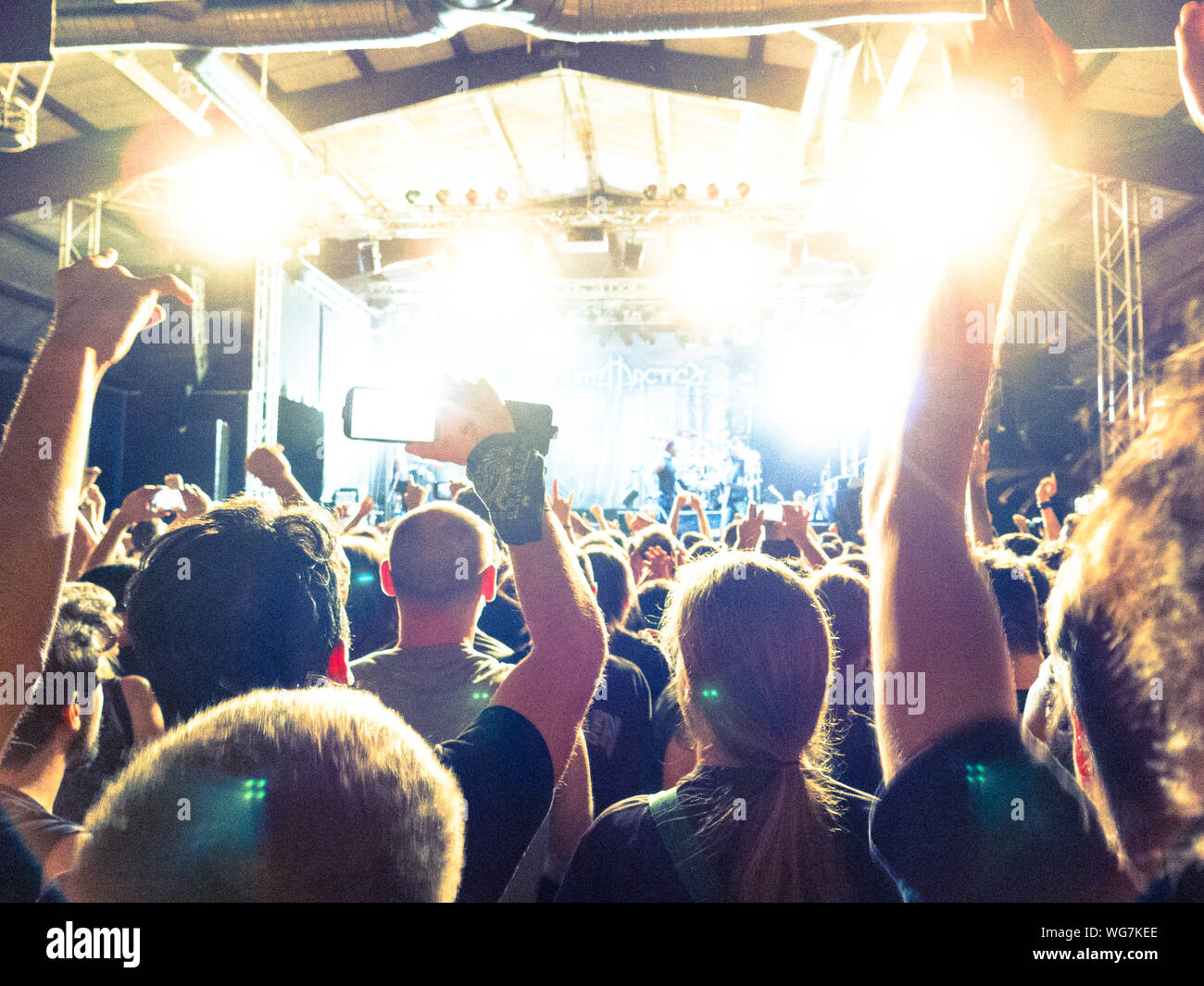 Concert crowd clapping in front of a bright stage Stock Photo - Alamy