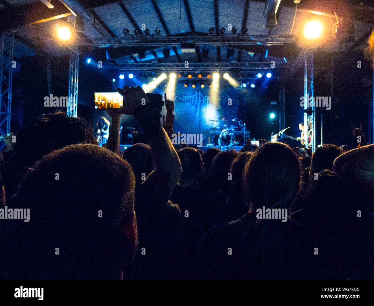 Concert crowd clapping in front of a bright stage Stock Photo - Alamy