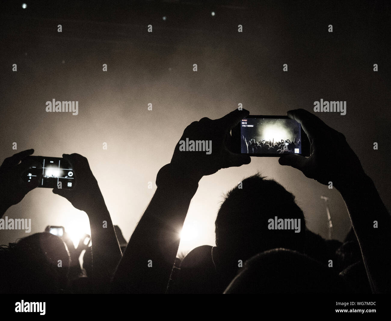 Concert crowd clapping in front of a bright stage Stock Photo - Alamy