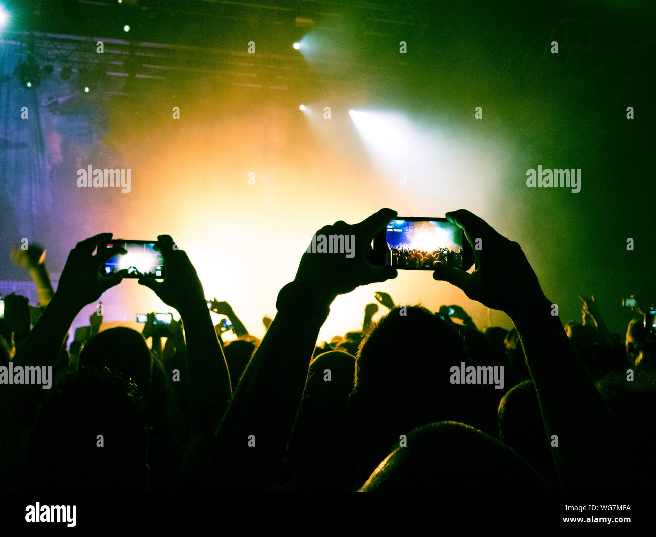 Concert crowd clapping in front of a bright stage Stock Photo - Alamy