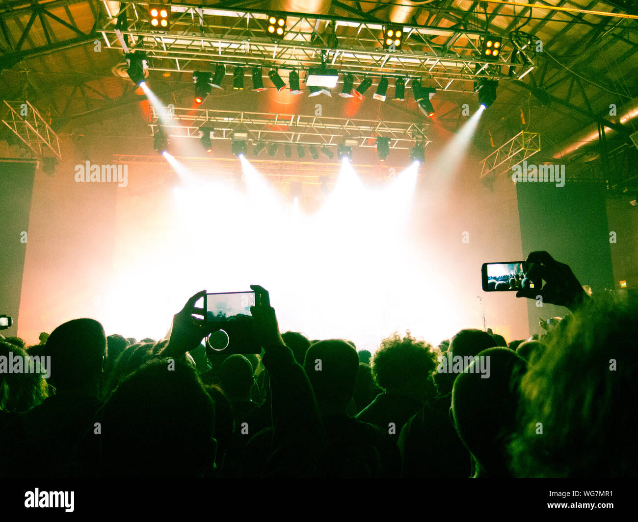 Concert crowd clapping in front of a bright stage Stock Photo - Alamy