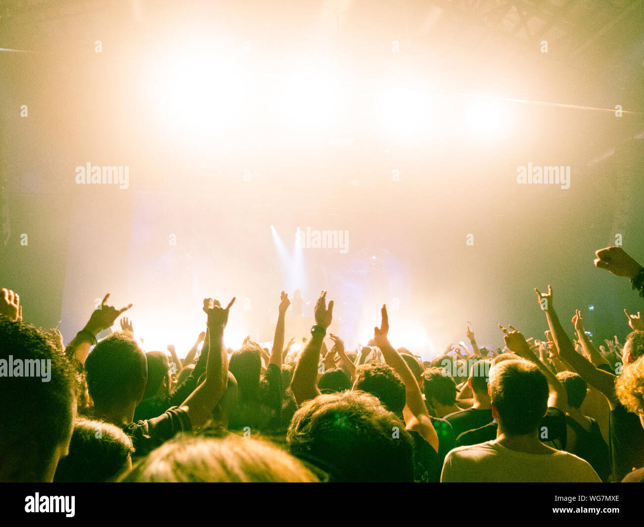 Concert crowd clapping in front of a bright stage Stock Photo - Alamy