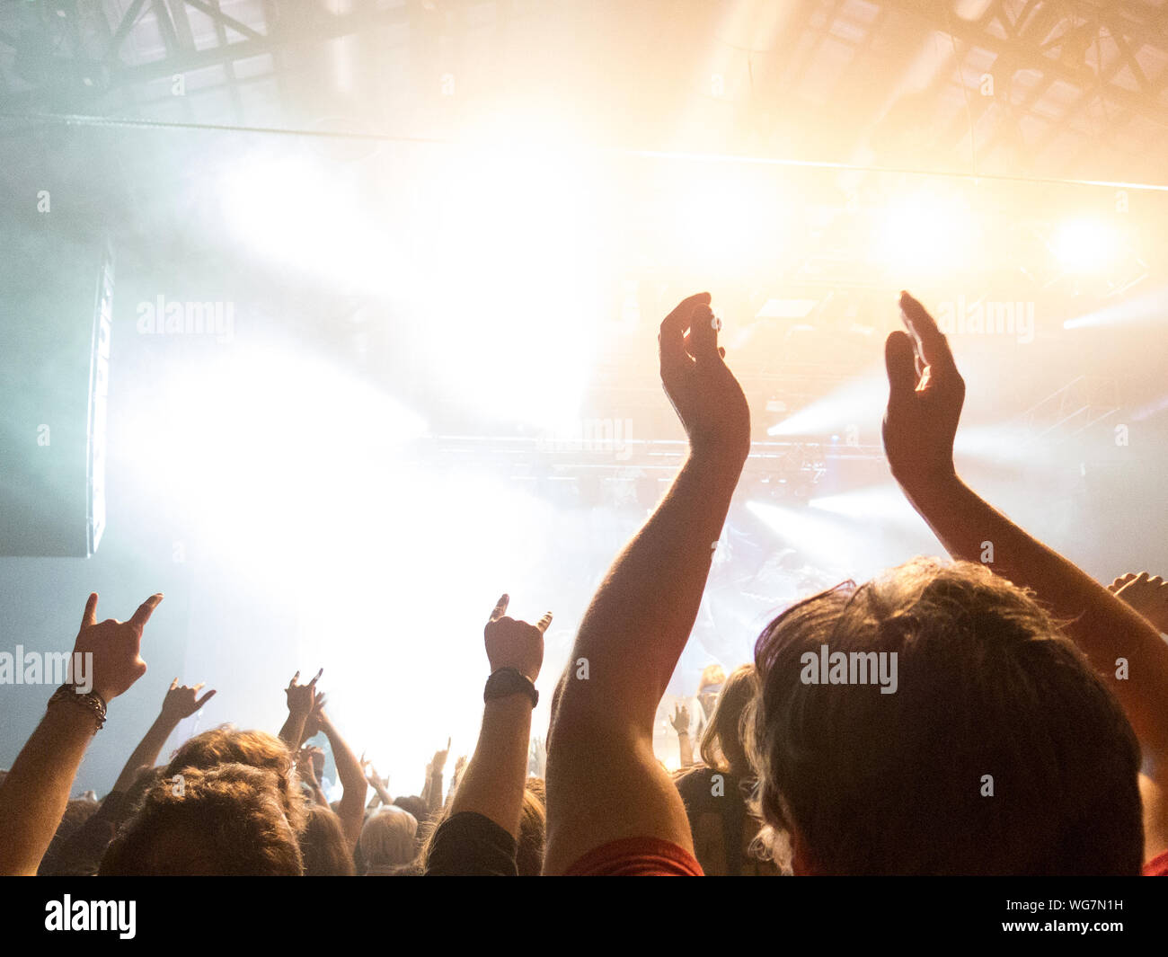 Concert crowd clapping in front of a bright stage Stock Photo - Alamy