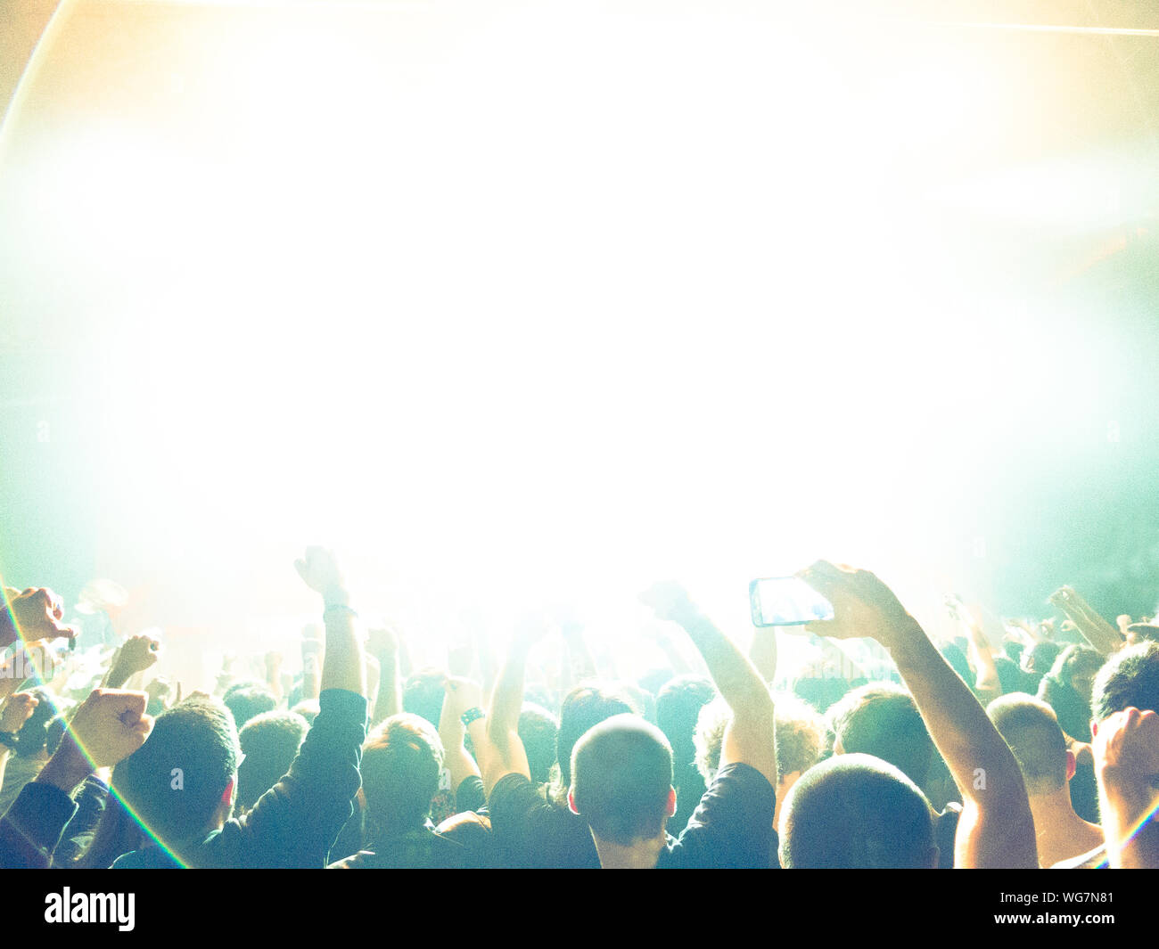 Concert crowd clapping in front of a bright stage Stock Photo - Alamy