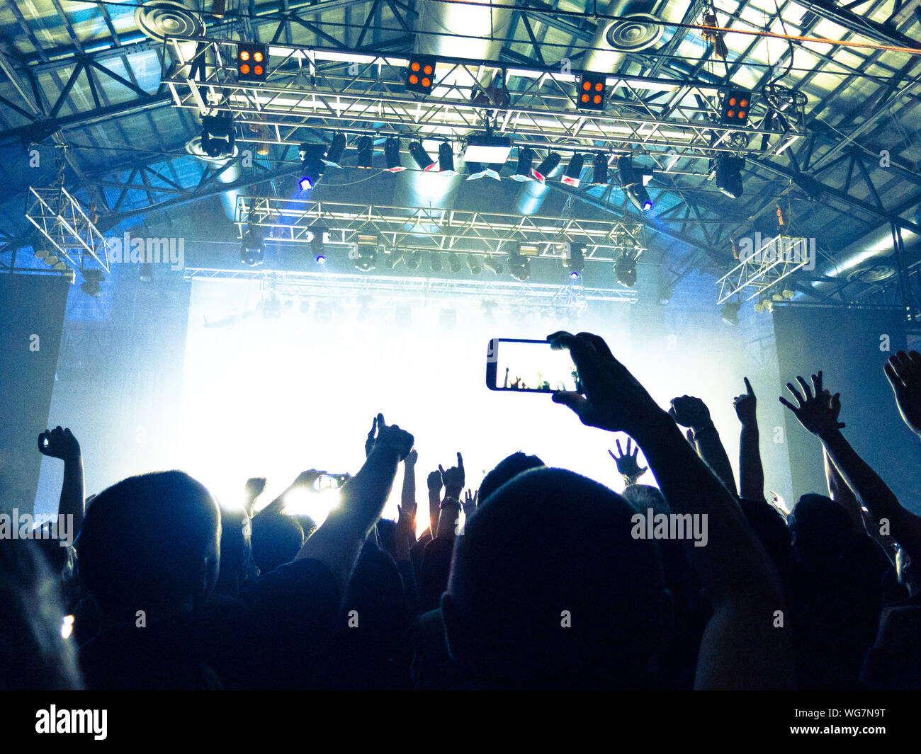 Concert crowd clapping in front of a bright stage Stock Photo - Alamy