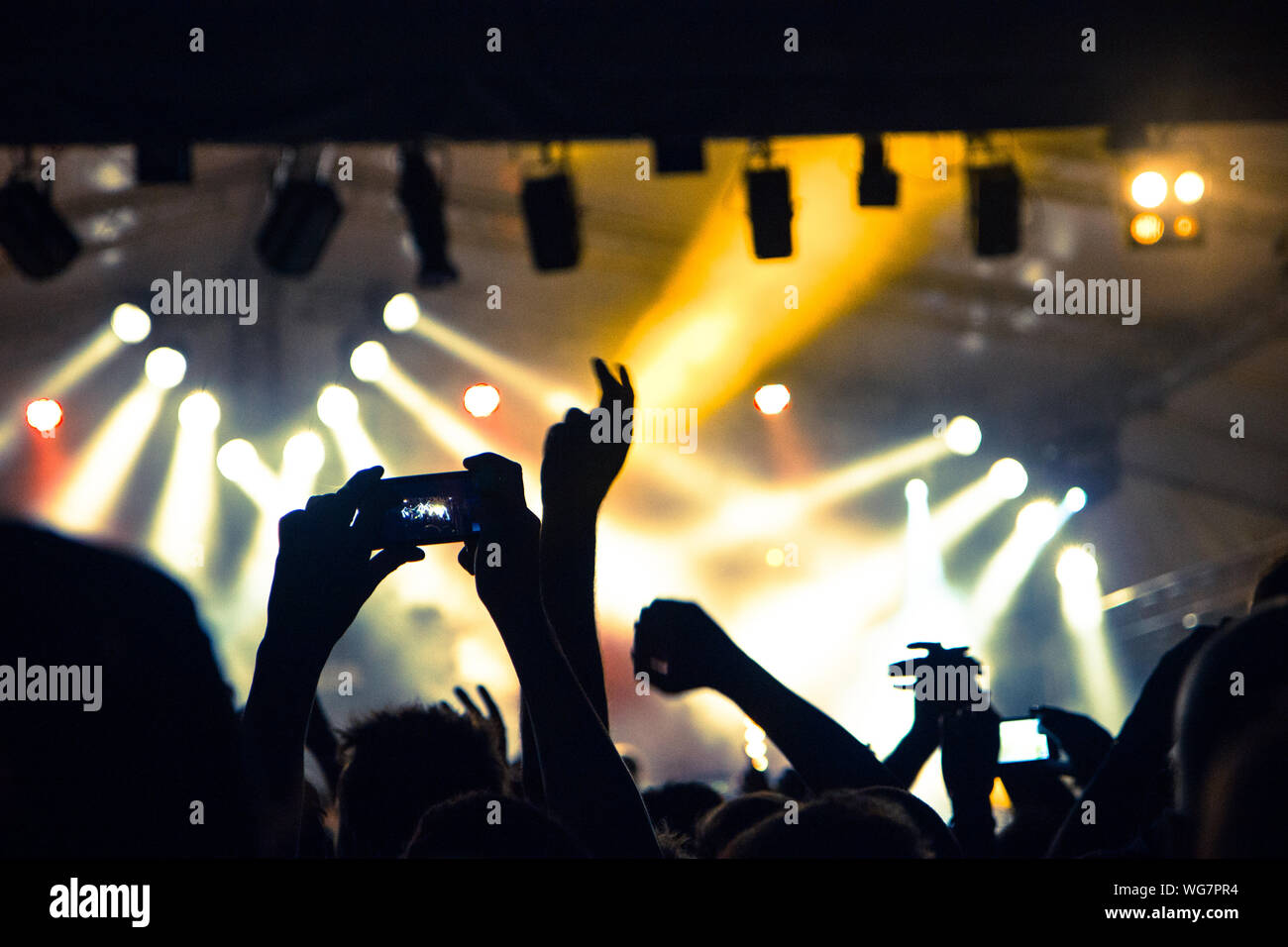 Concert crowd clapping in front of a bright stage Stock Photo - Alamy