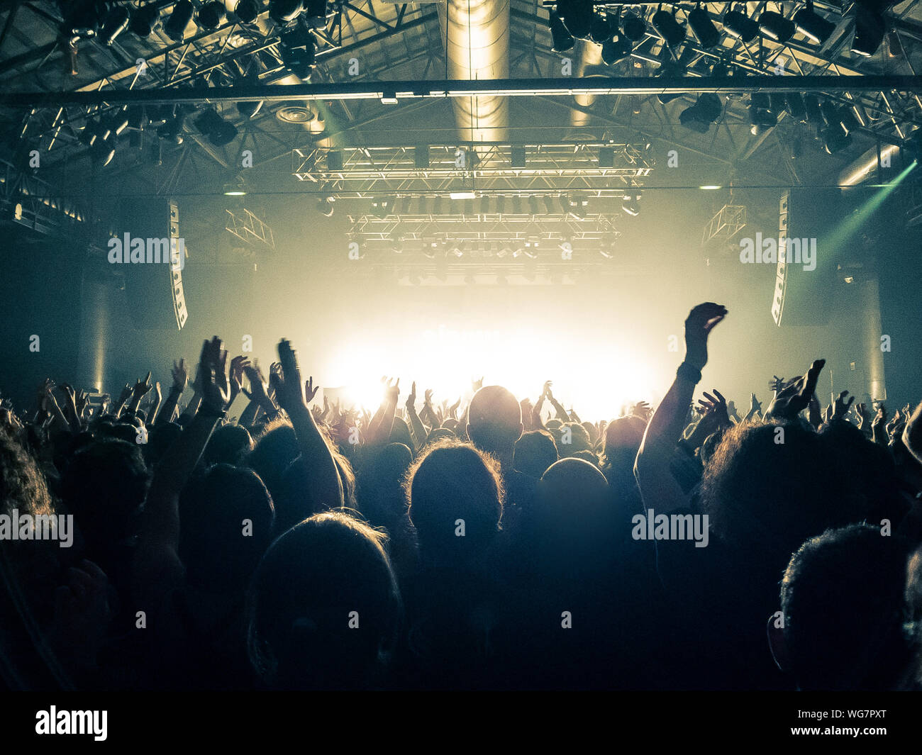 Concert crowd clapping in front of a bright stage Stock Photo - Alamy