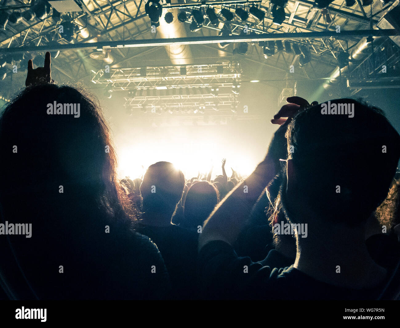 Concert crowd clapping in front of a bright stage Stock Photo - Alamy
