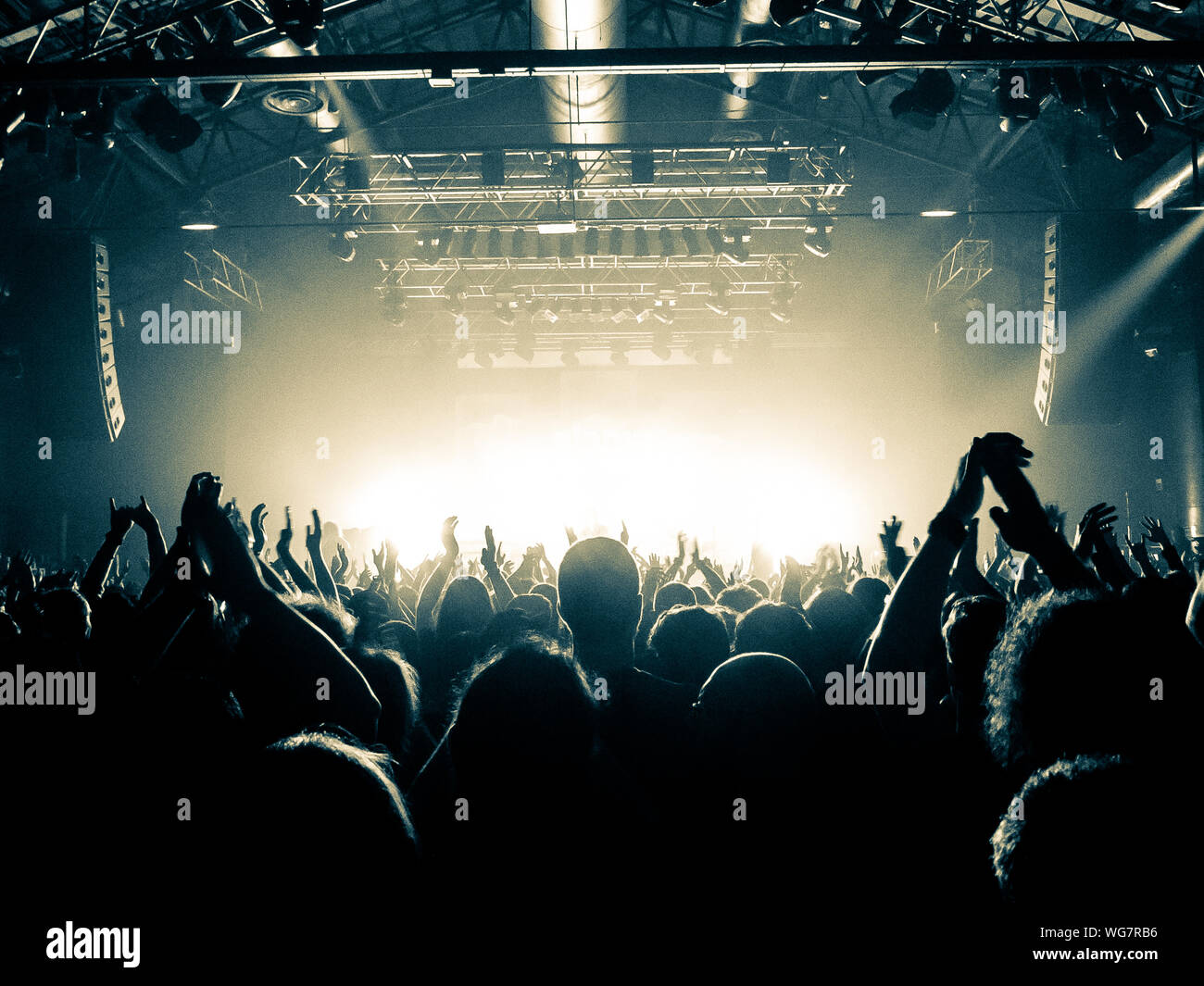 Concert crowd clapping in front of a bright stage Stock Photo - Alamy