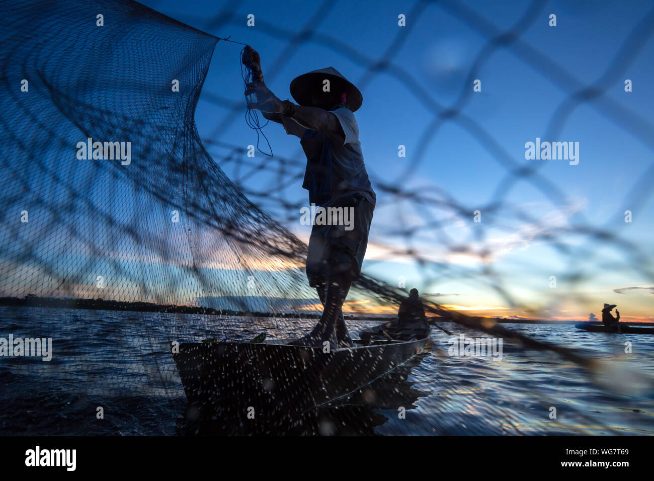 Silhouette fisherman throwing net in hi-res stock photography and ...