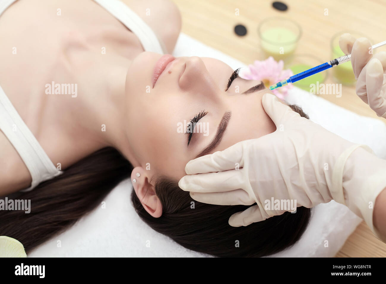 Hands of cosmetologist making injection in face, lips. Young woman gets ...