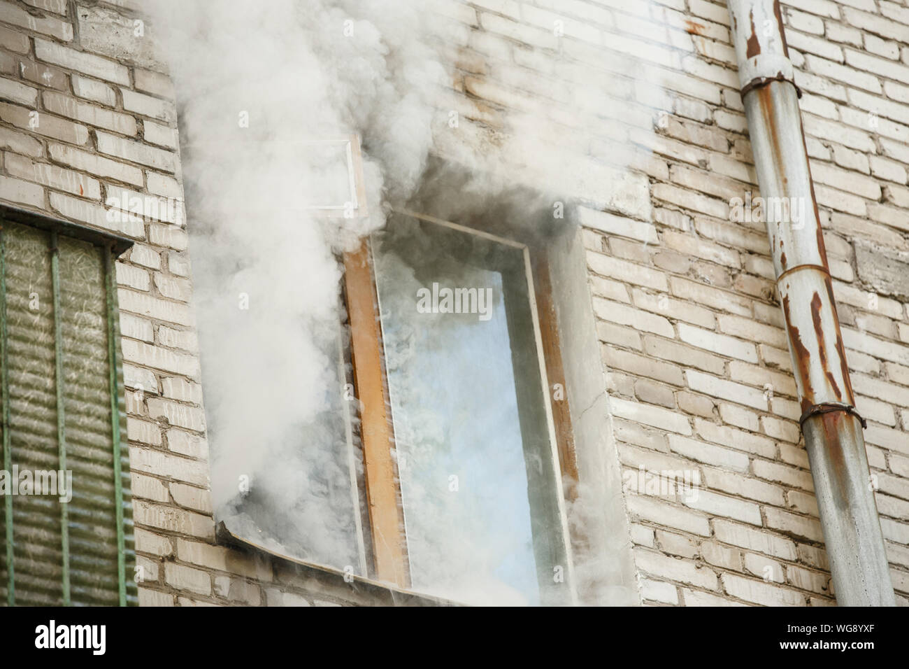 Image of brick house with smoke coming out of window during day Stock ...