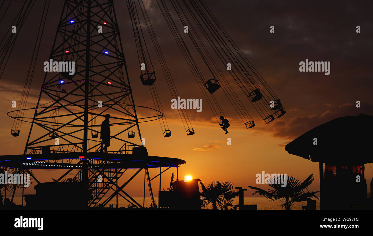 Swinging carousel roundabout chain ride at sunset. Entertainment on the ...