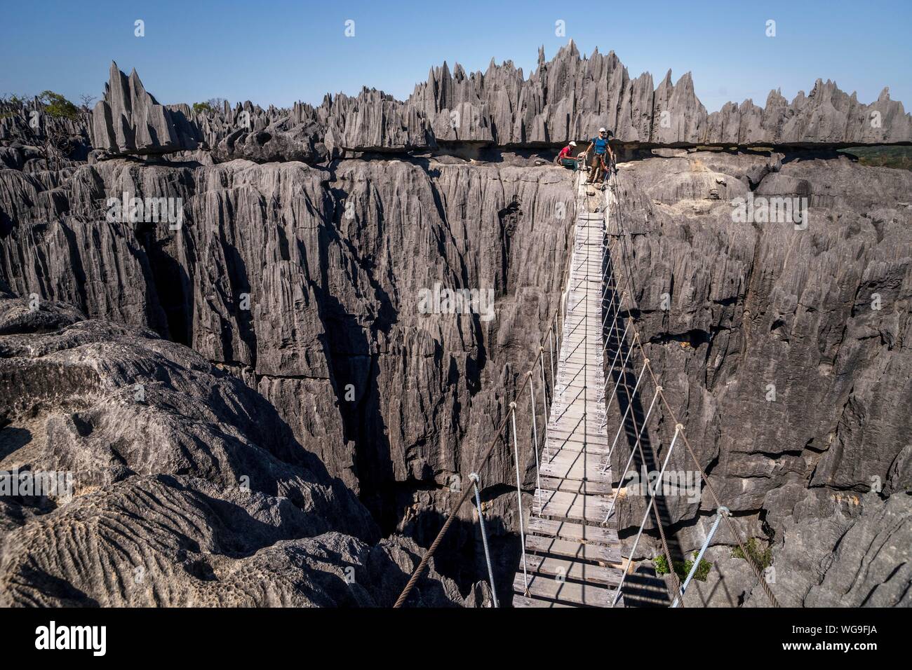 Tourist on suspension bridge over gorge in rugged limestone rocks ...