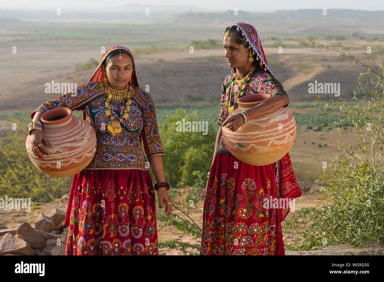 Two Ahir Women in traditional colorful clothes carrying water in a clay ...