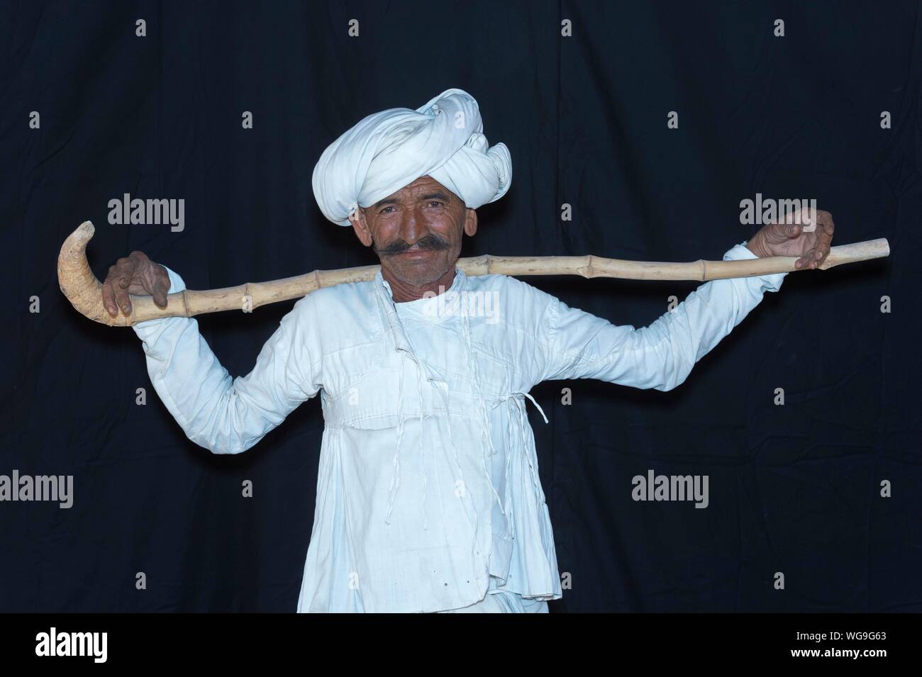 Rabari man wearing white clothes with turban holding walking stick hi ...