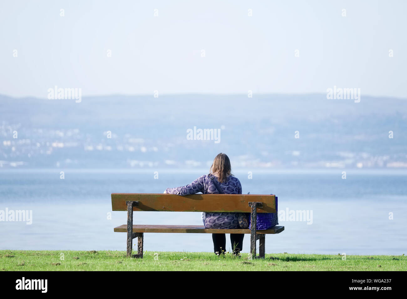 Single lady lonely on park bench at the sea enjoy peace and quiet for ...