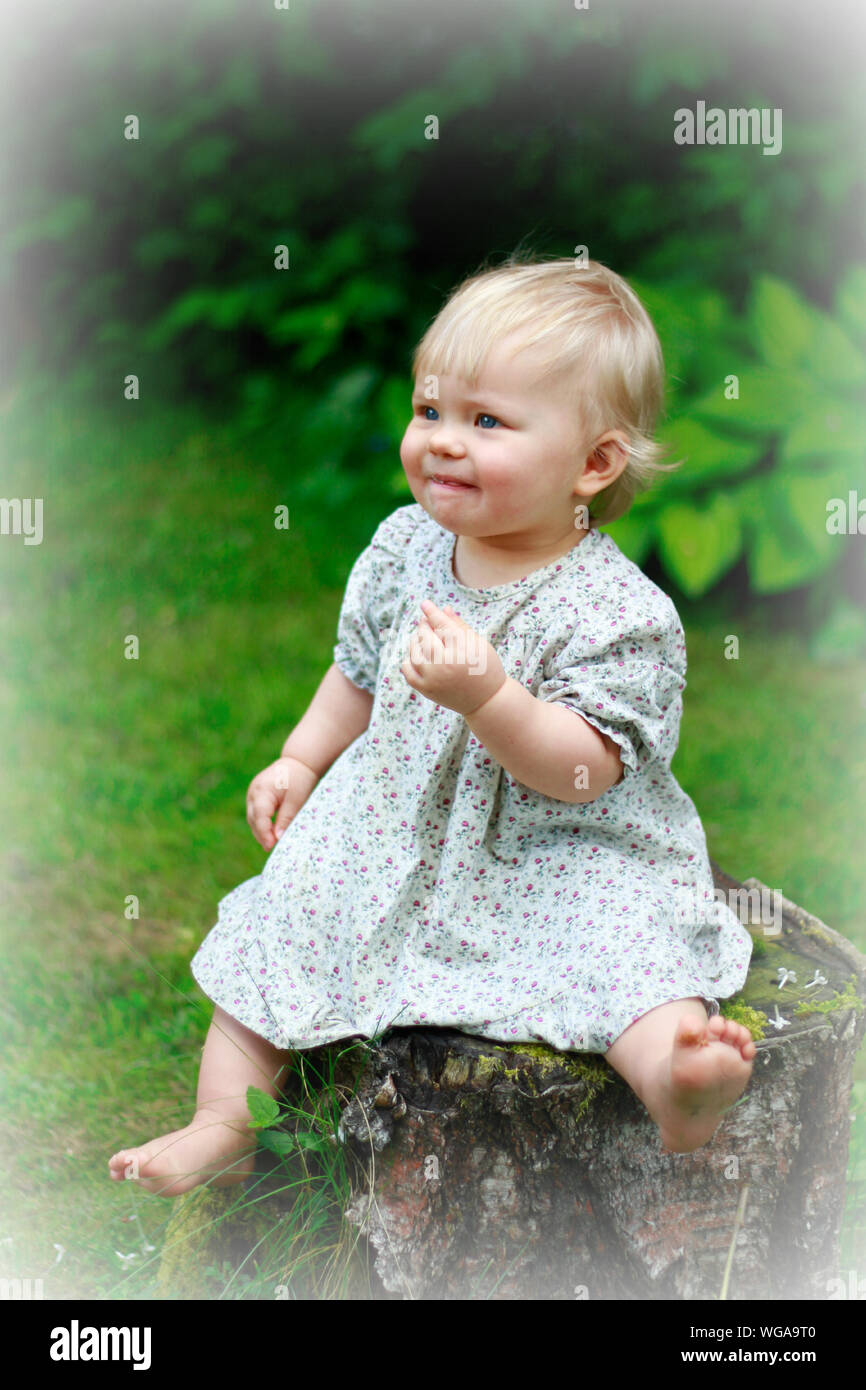 Baby girl sitting on stump hi-res stock photography and images - Alamy