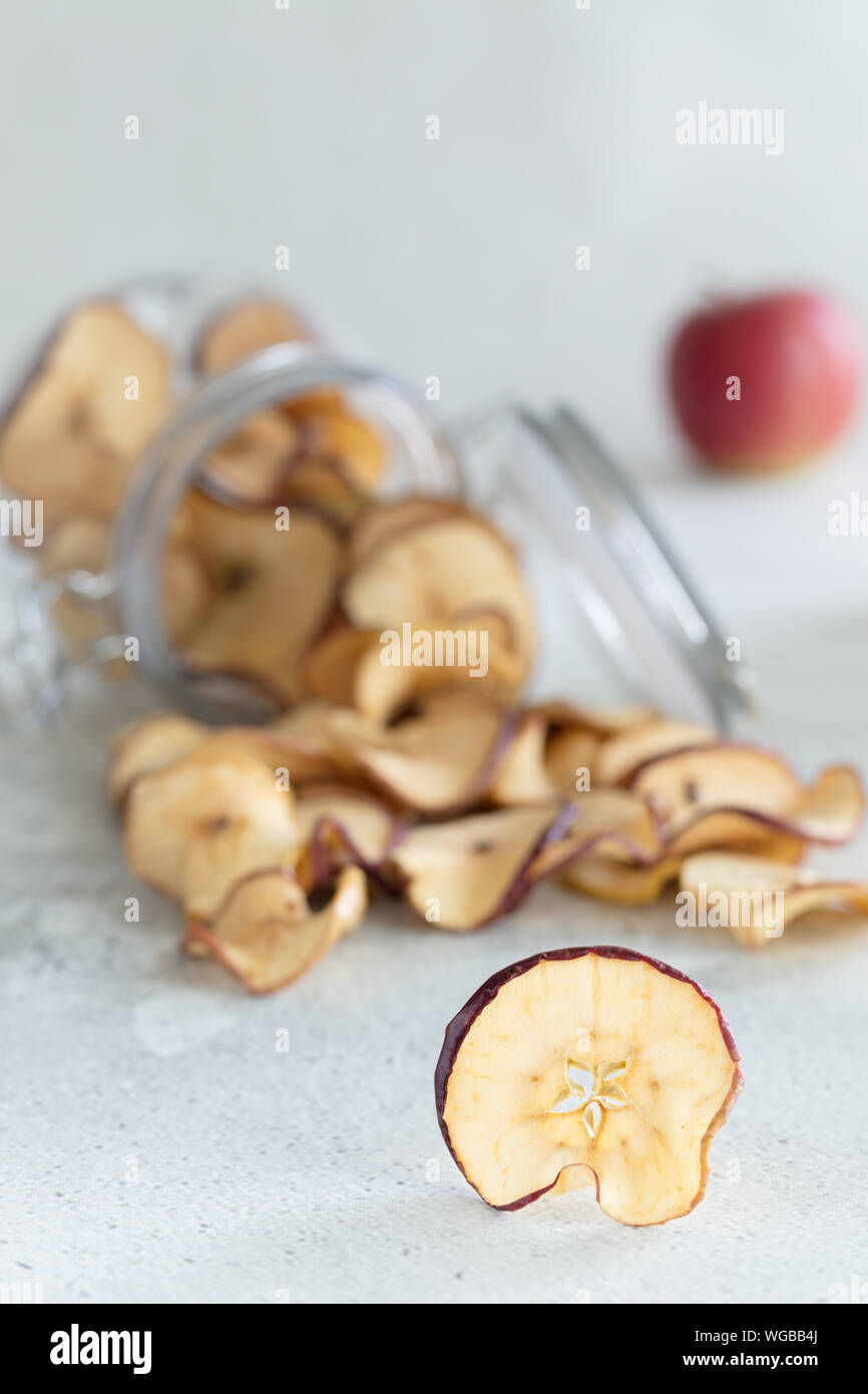 Dried apples chips in glass jar on light background, vertical ...