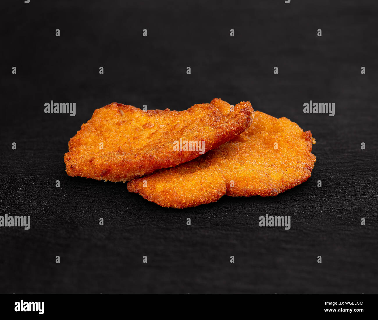 Two chicken breaded schnitzel on black background Stock Photo - Alamy