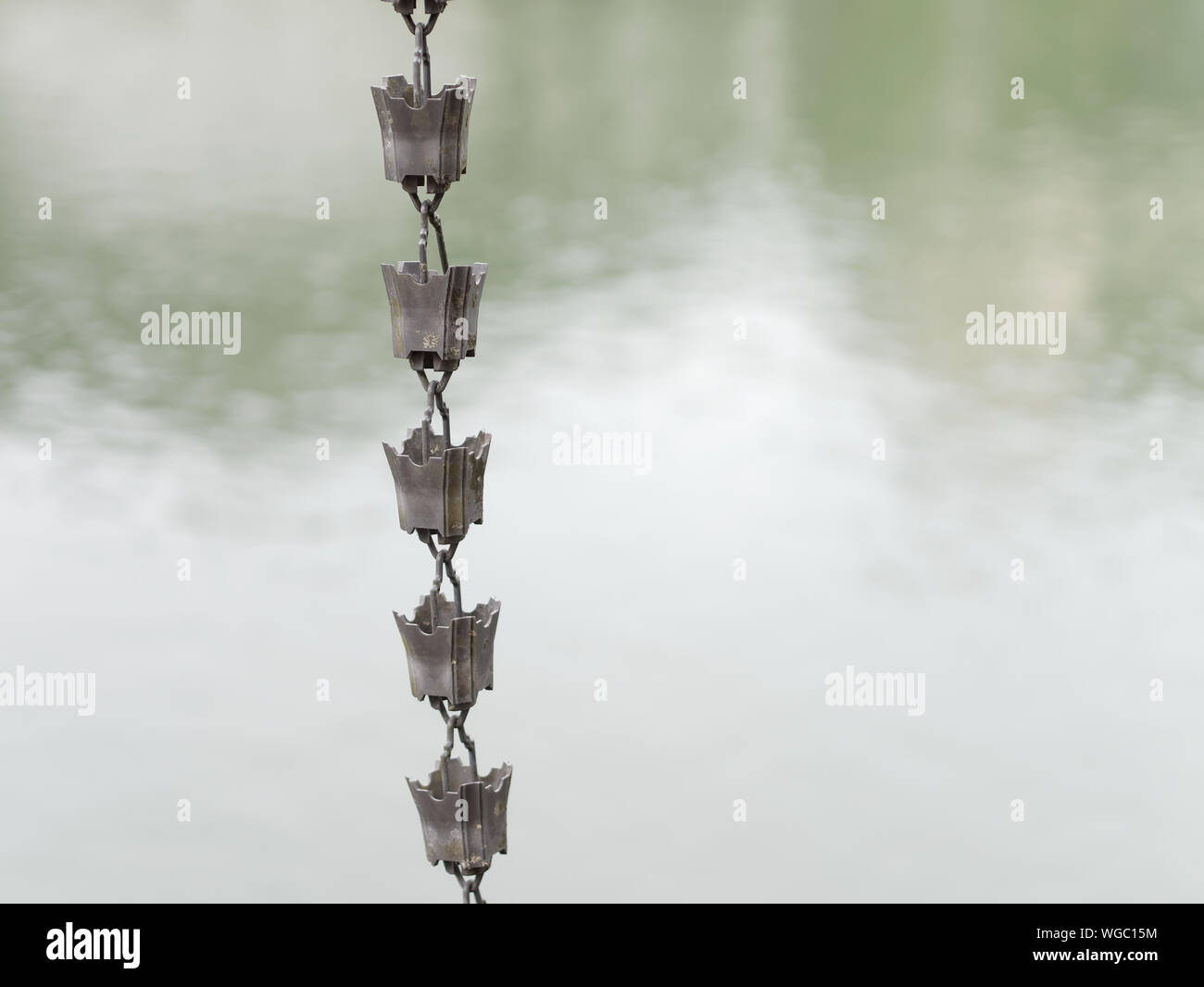 Close-up of Japanese rain chain. Lake's water surface with reflection ...