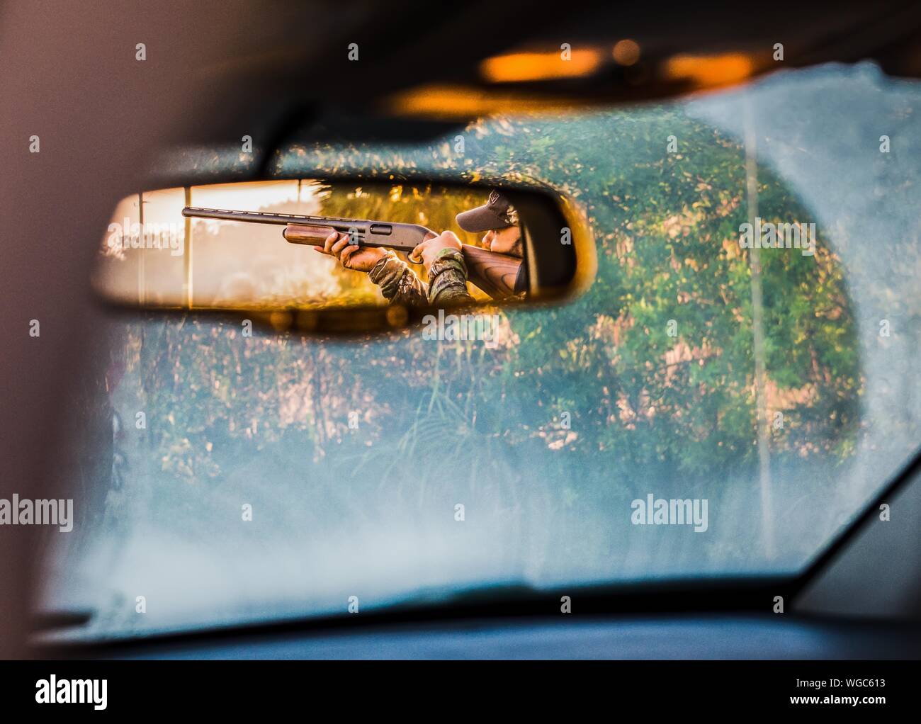Hunter Aiming With Shotgun Reflecting In Rear-view Mirror Of Car Stock ...