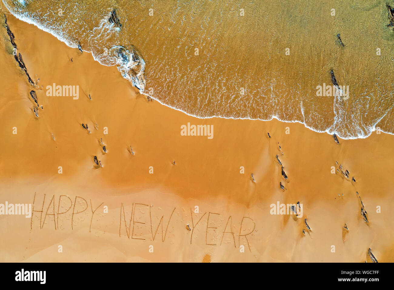 Aerial top shot from ocean waves and handwritten Happy New Year at the ...