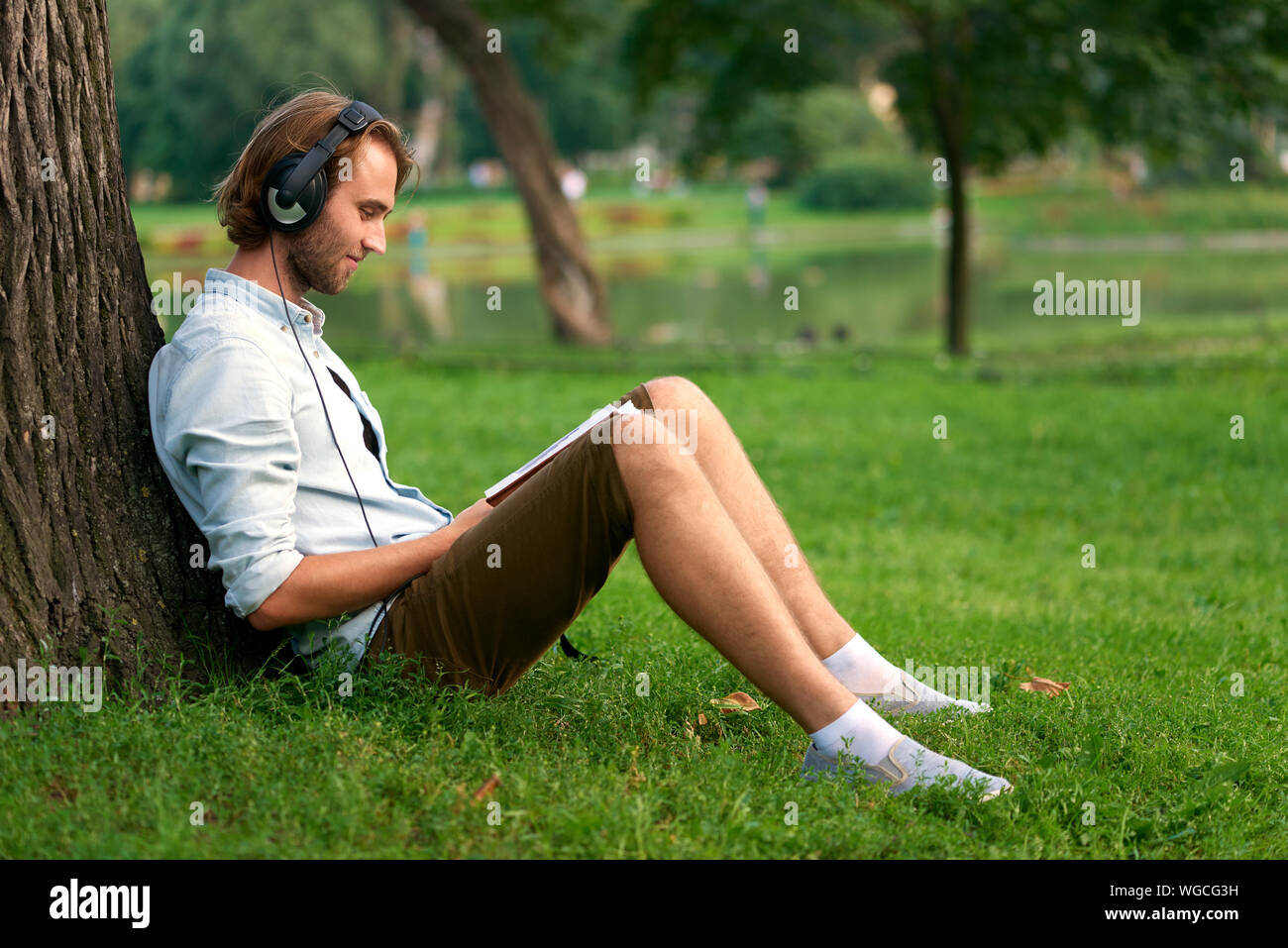 Student with headphones in park of campus read a book Stock Photo - Alamy