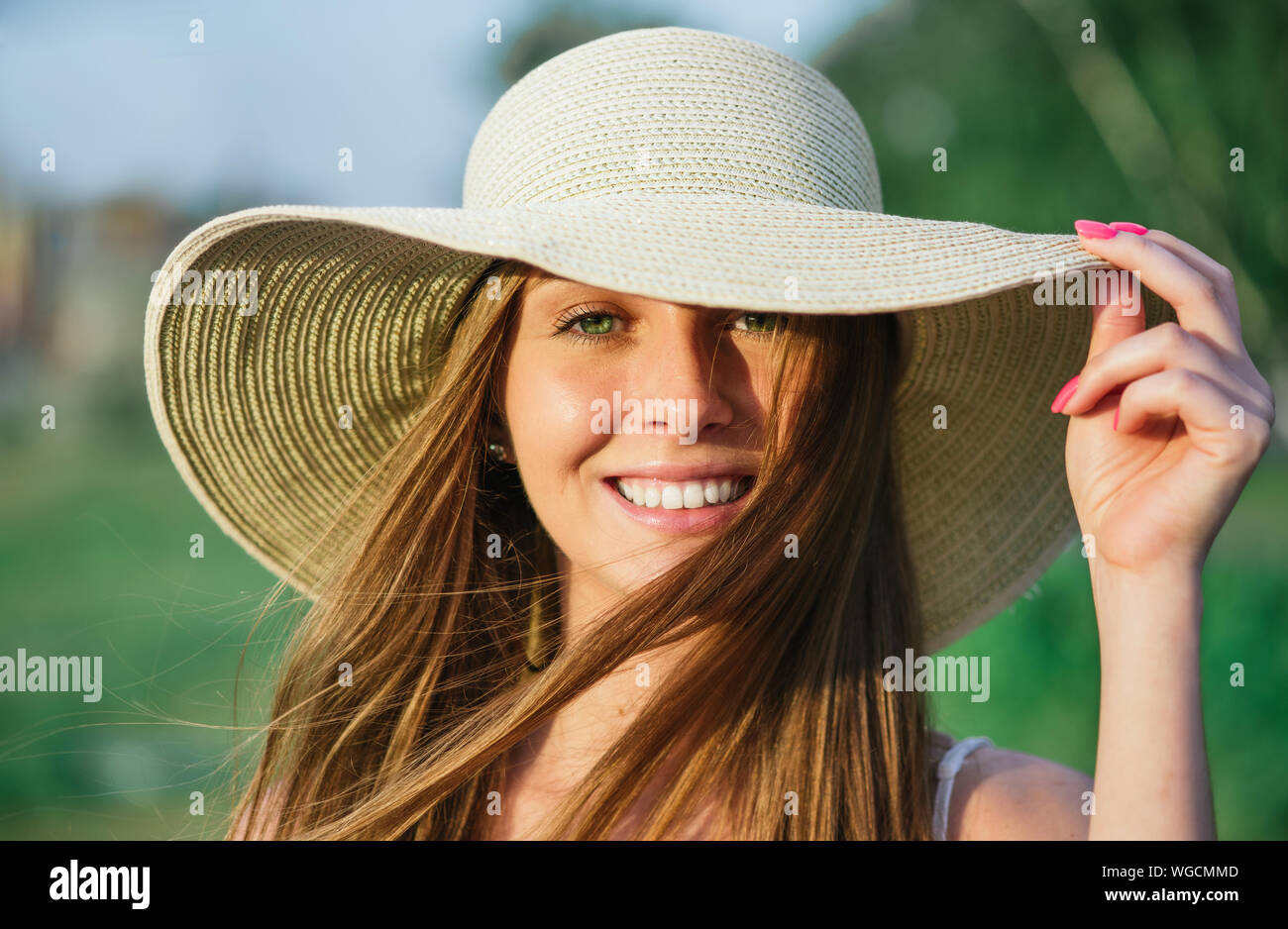 Young smiling beauty woman in summer hat over green background. Half ...