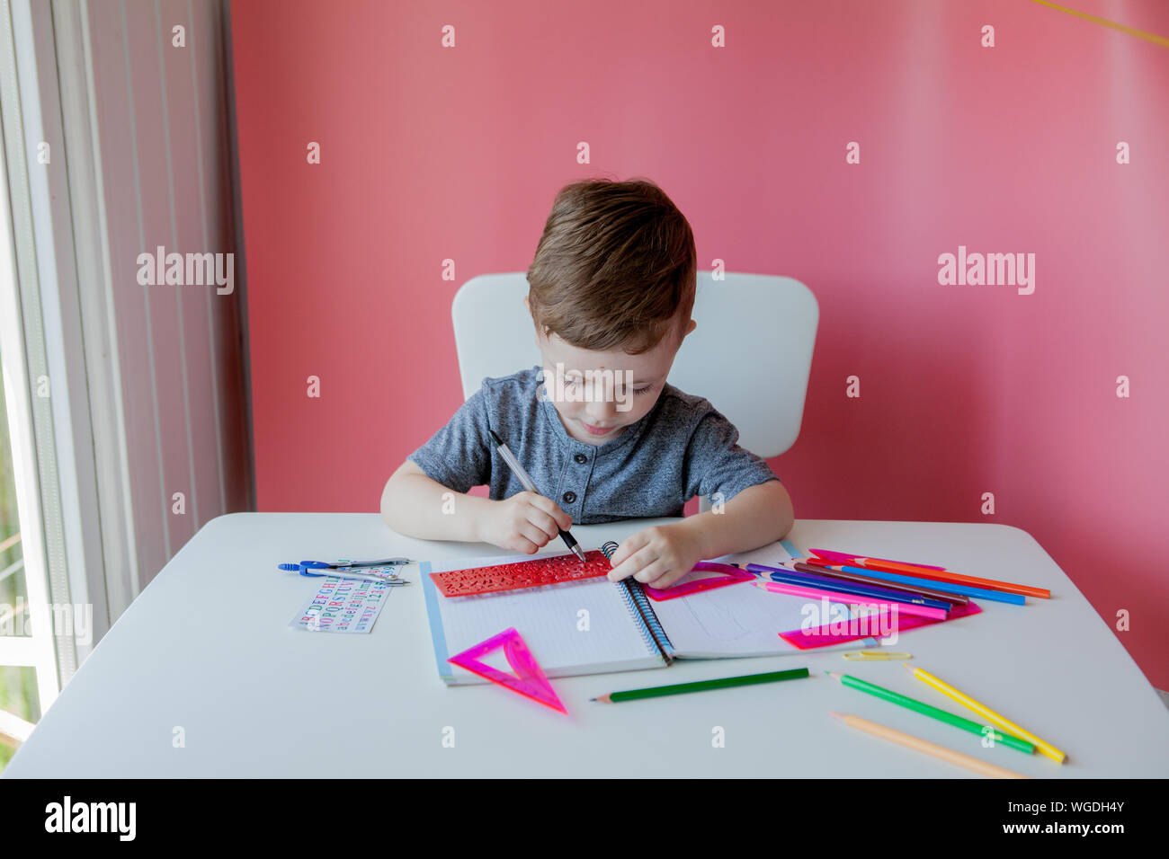 Portrait of cute kid boy at home making homework. Little concentrated ...