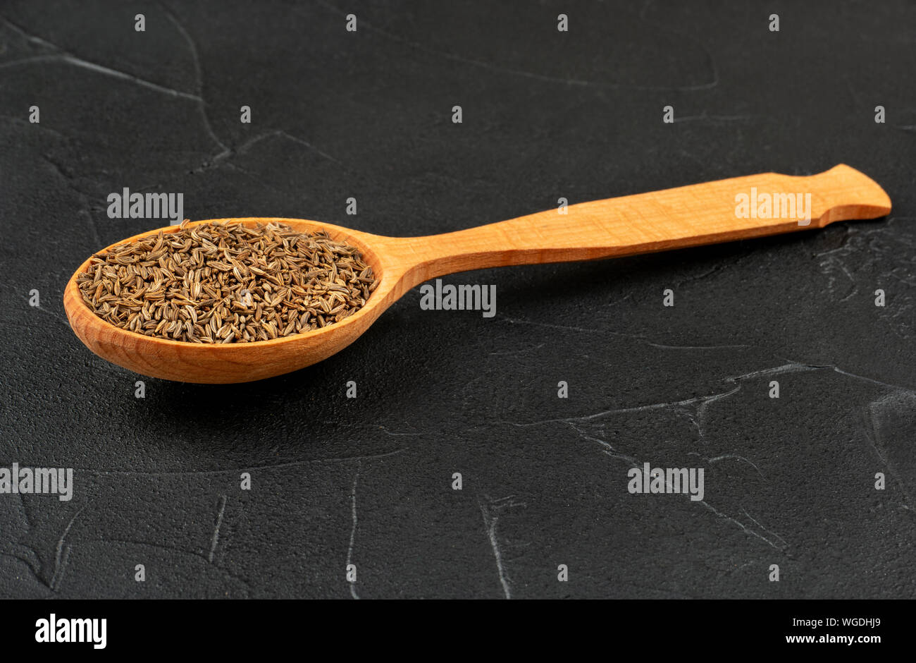 Dry cumin in sDry cumin in a large wooden spoon on a dark ...