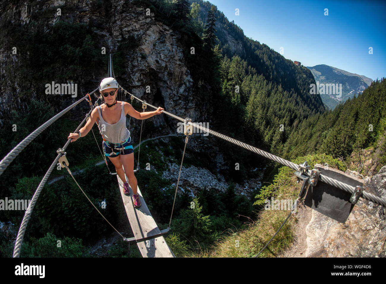 A woman climbs the via ferrata above Lac de la rosière near the French ...