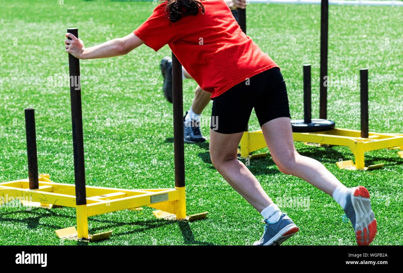Two high school teenagers pushing yellow weight sleds during track and ...
