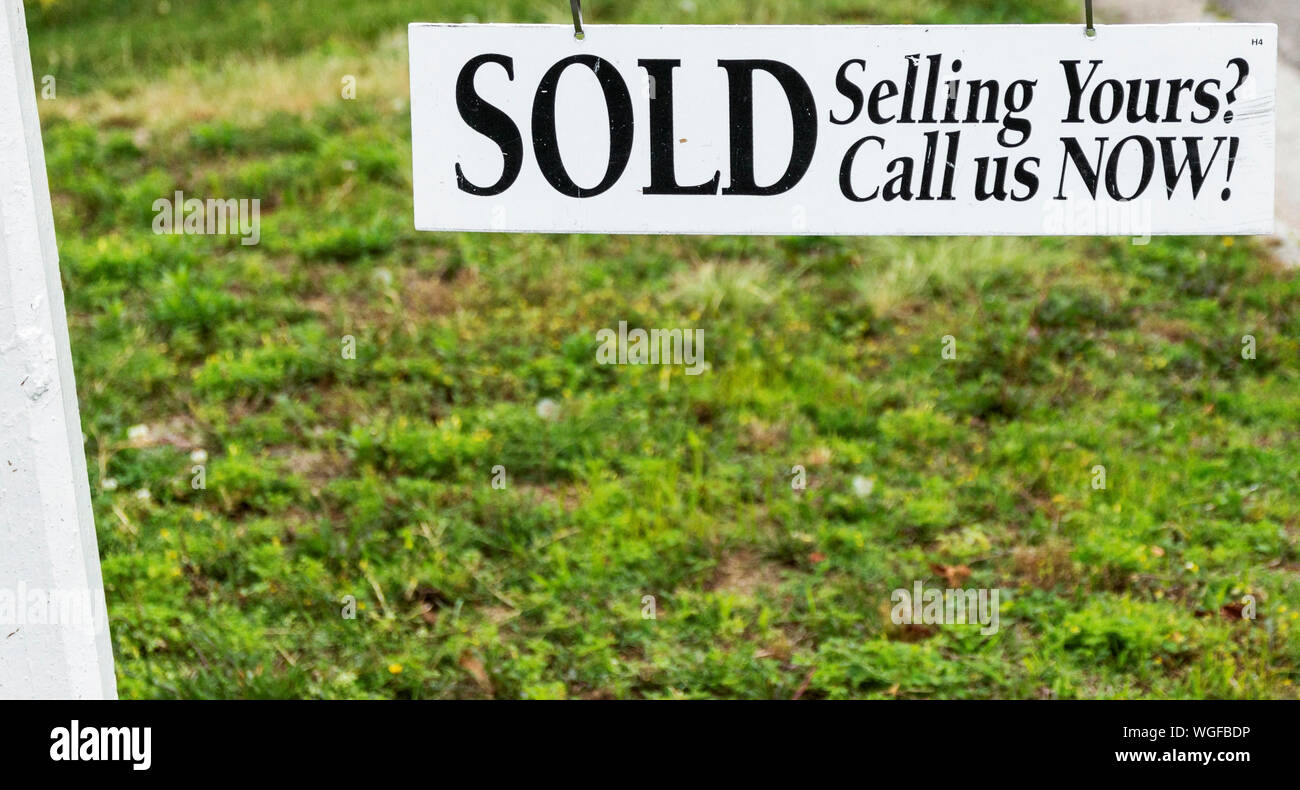 A white sold sign with black letters hanging over grass with room for ...