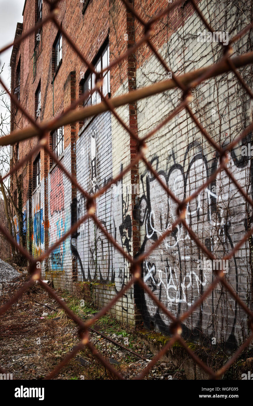 A once proud building has been left to rot behind a chain link fence ...