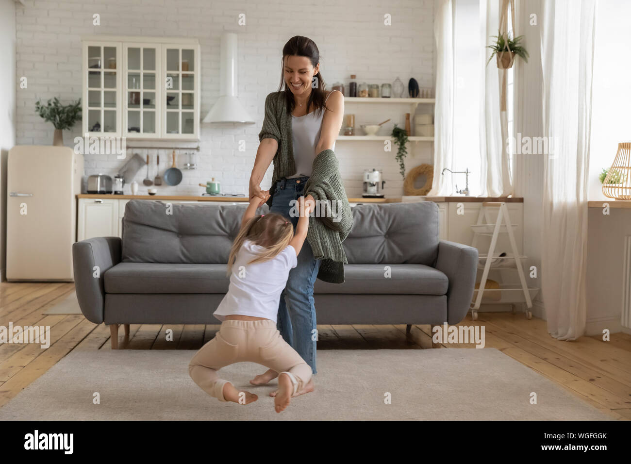 Beautiful woman spinning in circle little daughter in living room Stock ...