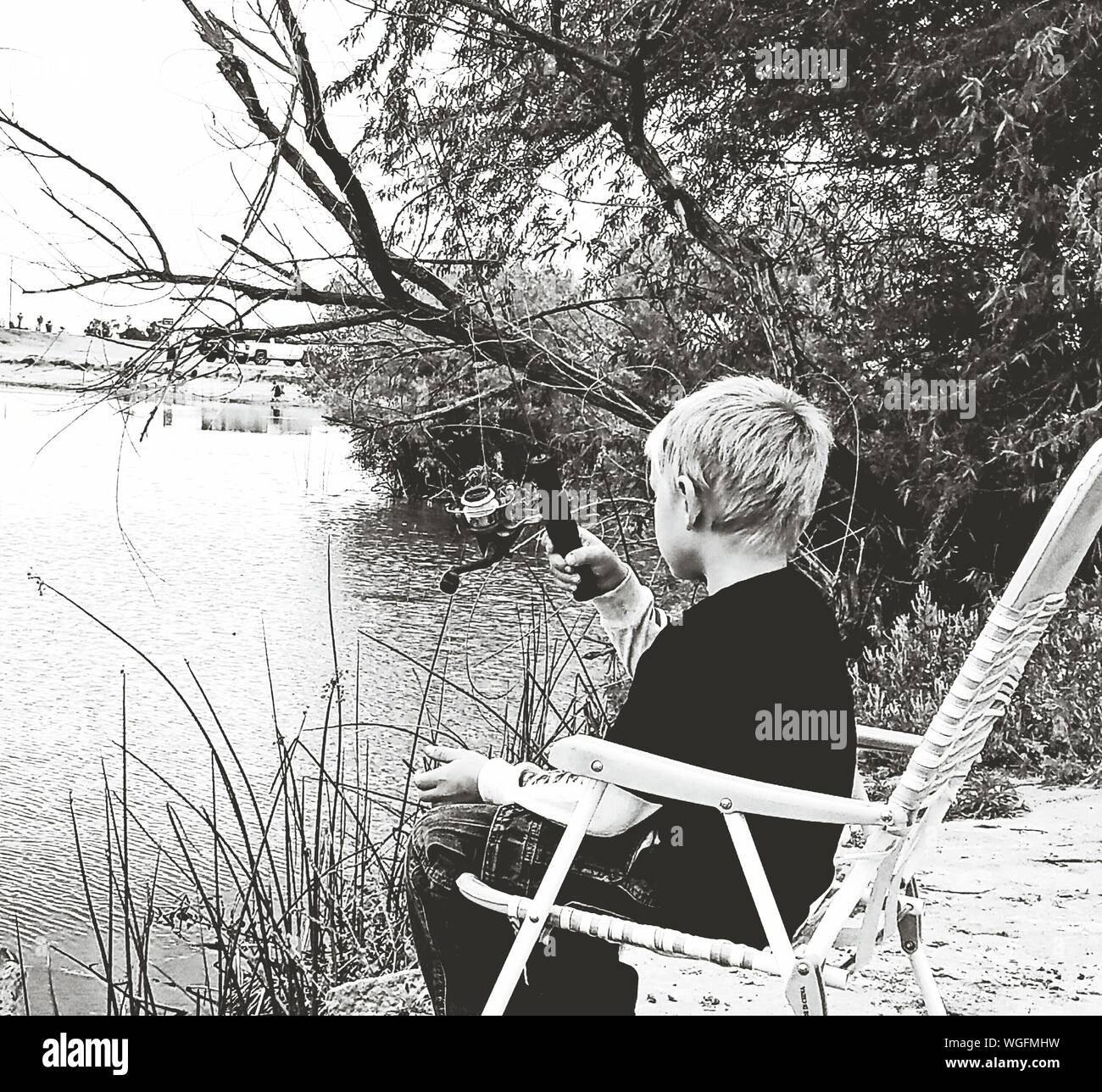 Side View Of Boy Fishing While Sitting On Chair At Lakeshore Stock ...