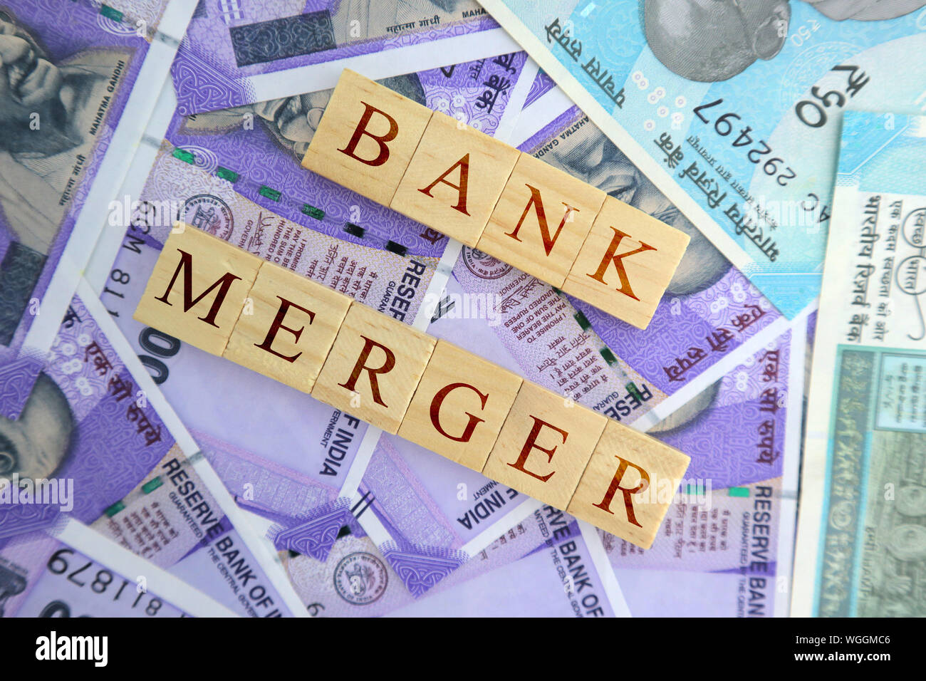 Concept of bank merger in wooden blocks on Indian currency notes Stock ...