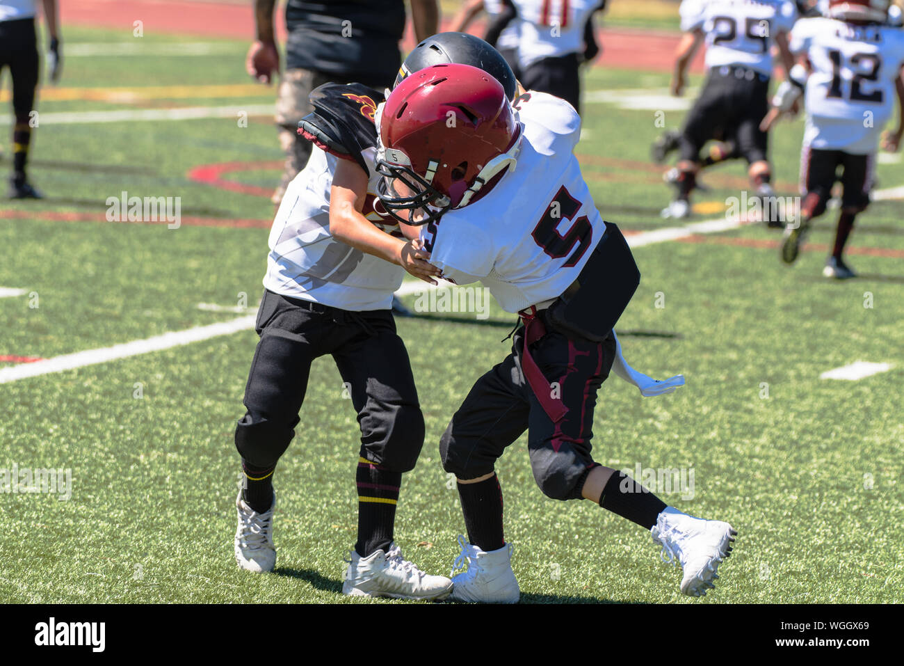 Opposing youth football players locked in each others grasp as they ...