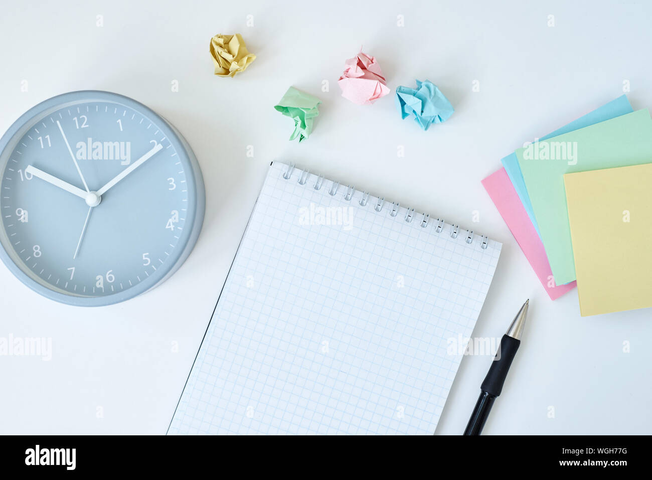 Gray round alarm clock colorful sticky notes and notebook on a white ...