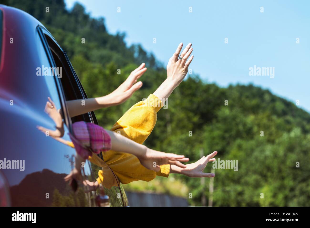 hands of men and children peering out of a car window on a background ...