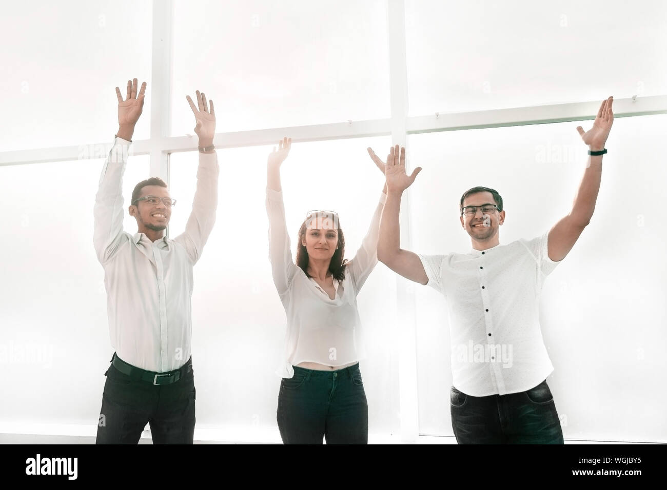 successful business team stands with hands up. photo with copy space ...