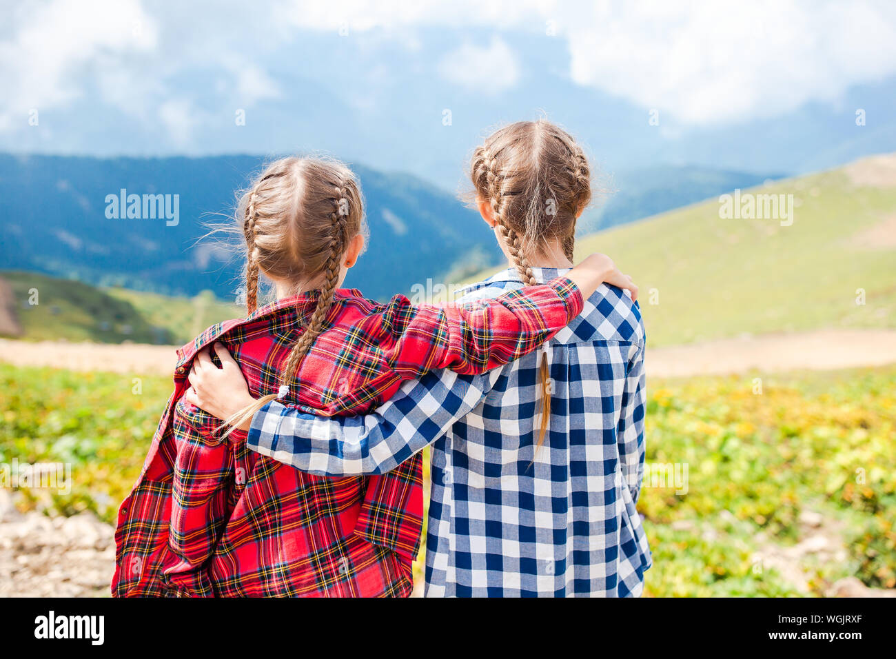 Back view of friendly kids in mountains in the background of the sky ...